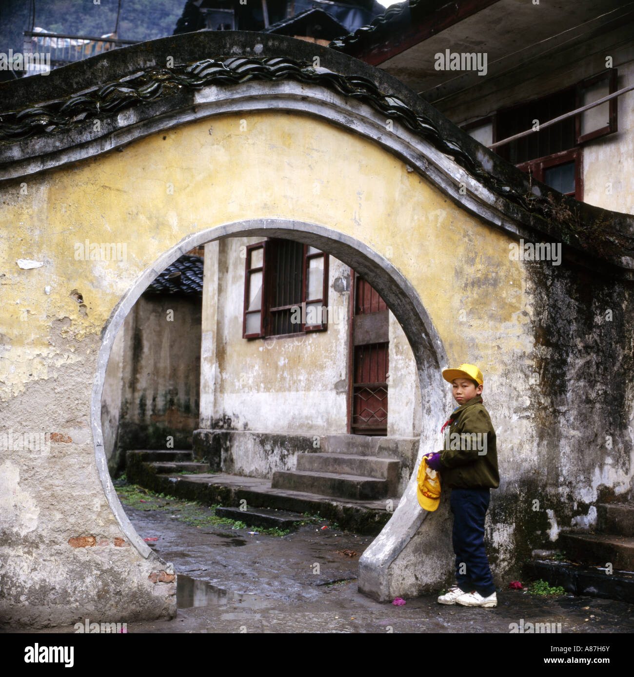 Young local boy by large traditional style stone arch over road ...