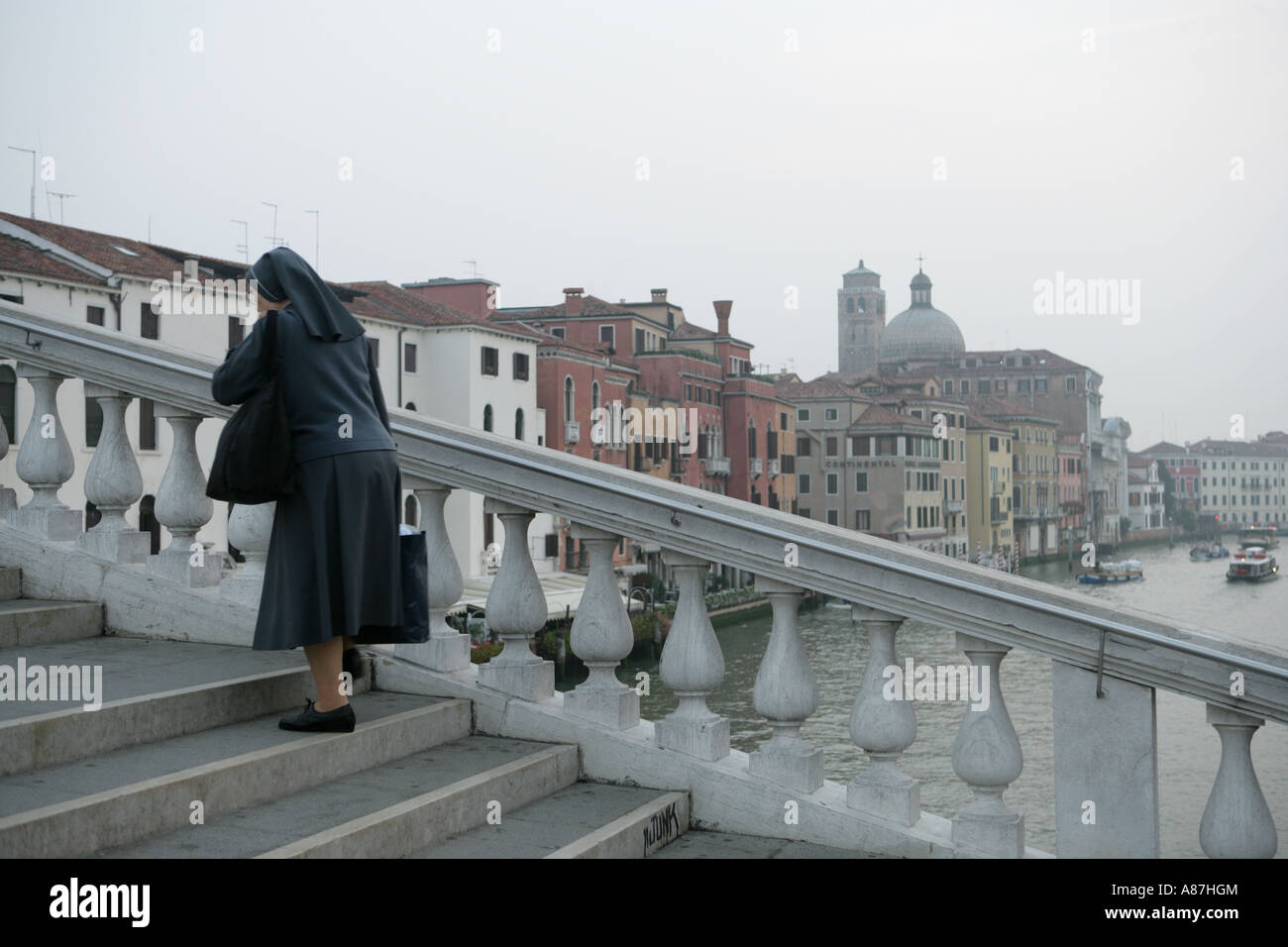 Nun climbing stairs by canal Stock Photo - Alamy