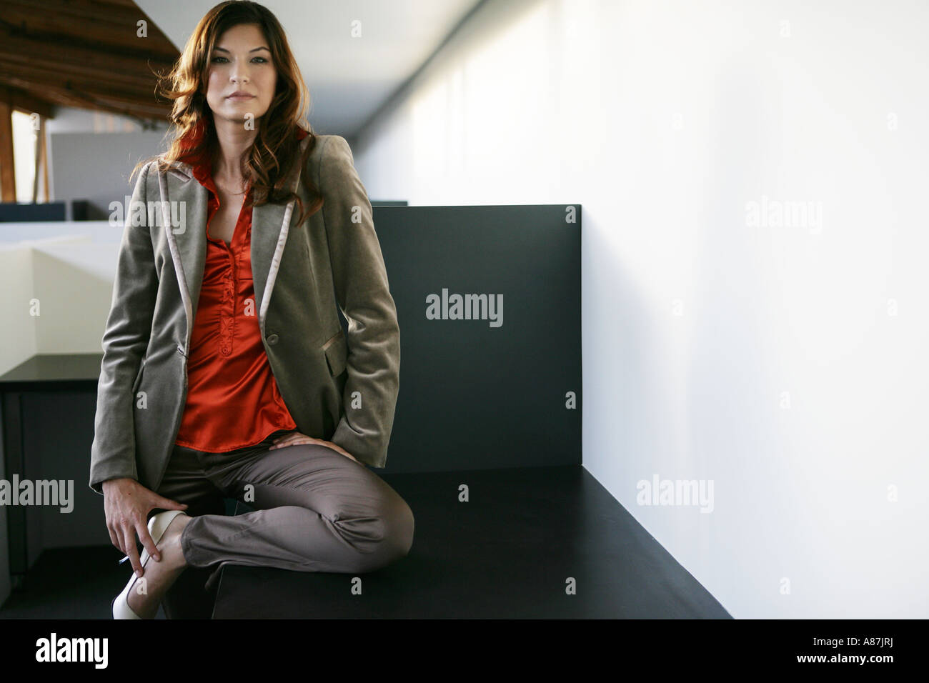 Woman with one leg on a desk, looking at camera Stock Photo - Alamy