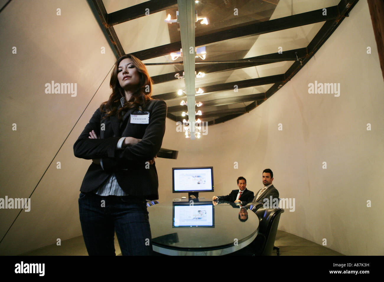 Three people inside a conference room, woman standing apart Stock Photo ...