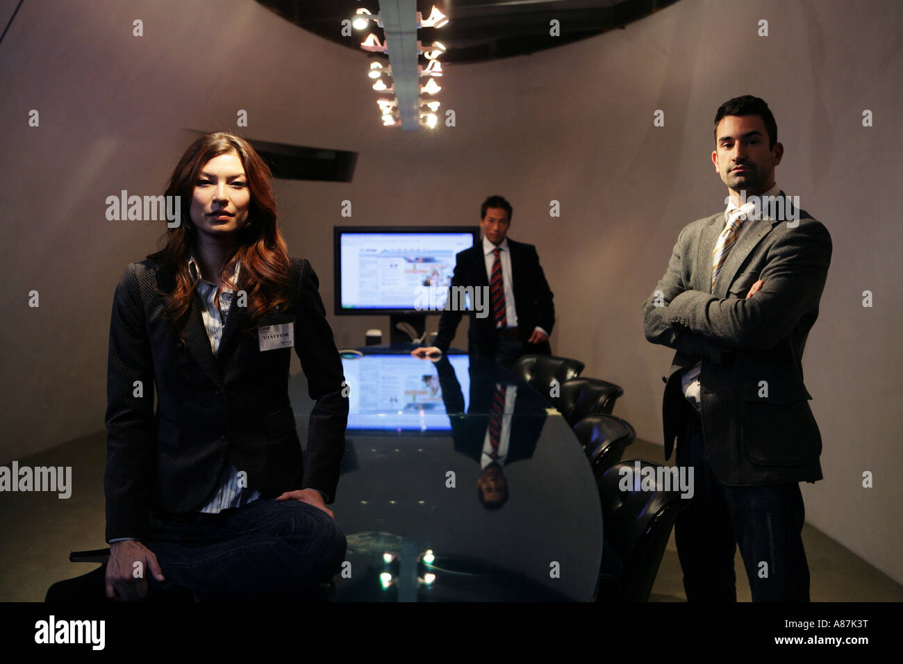 Three people inside a conference room, looking at camera Stock Photo ...