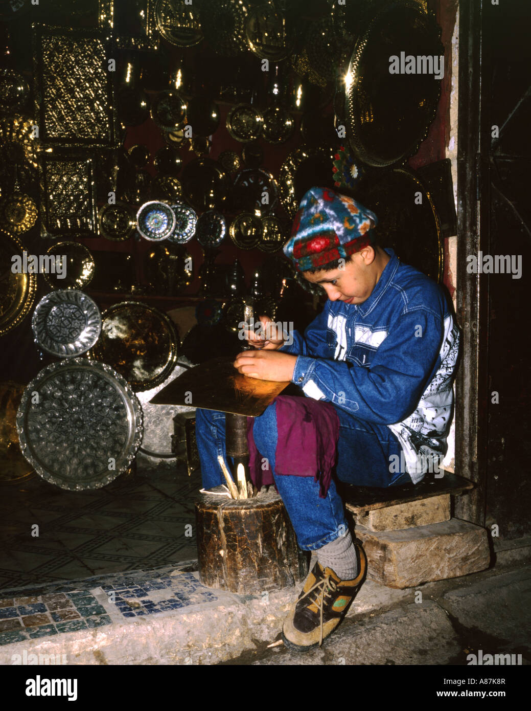 Young local boy working on a handicraft at the family metalwork shop in ...