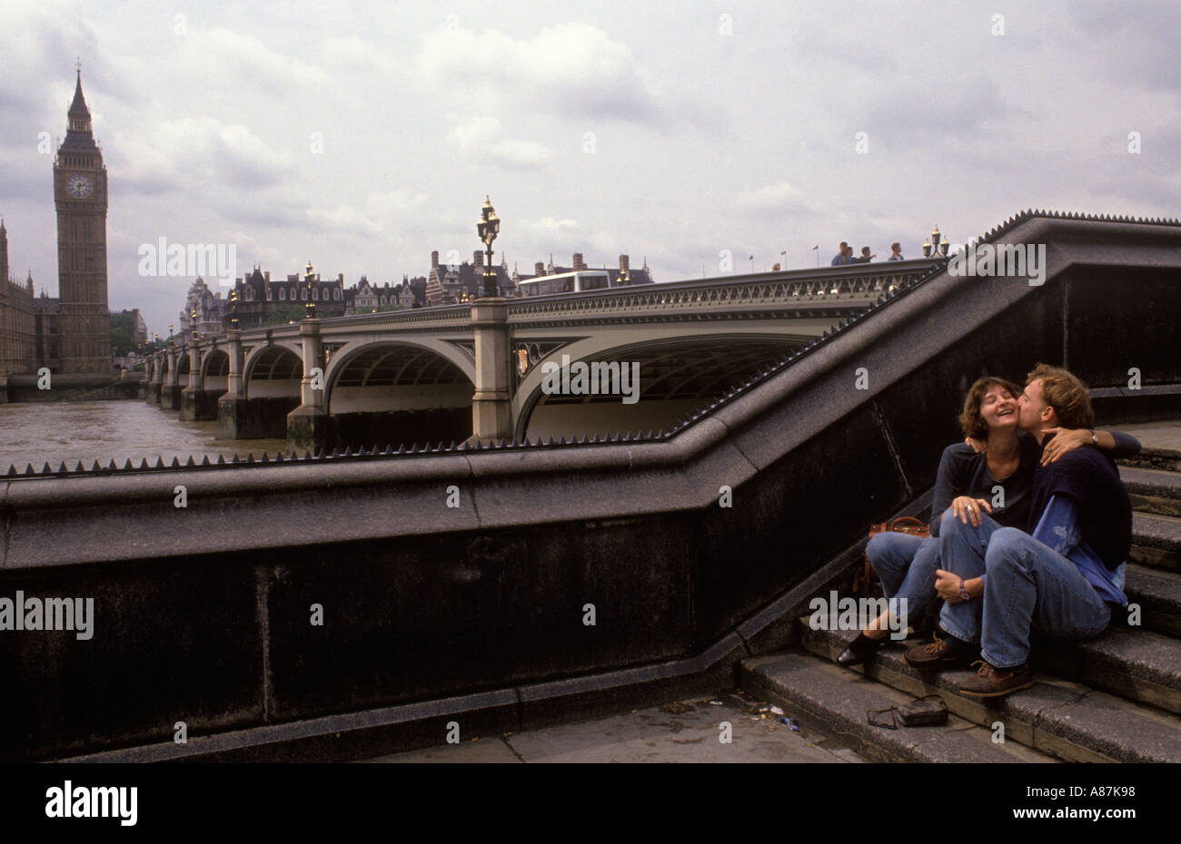 A young couple kiss and embrace each other on Westminster Bridge ...