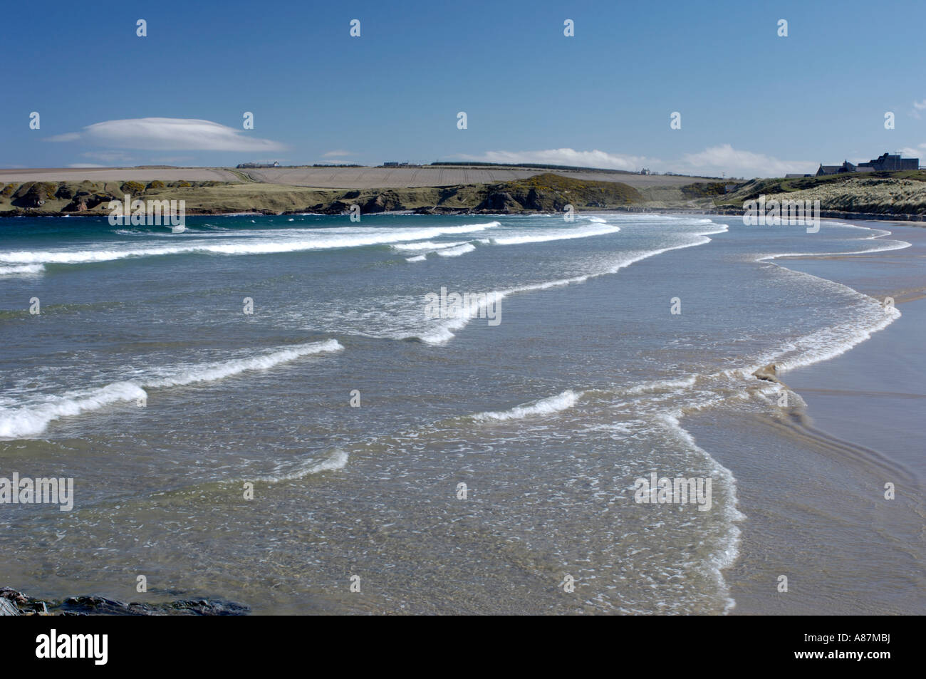 Long Waves roll in across the shallow beach at Sandend Bay ...