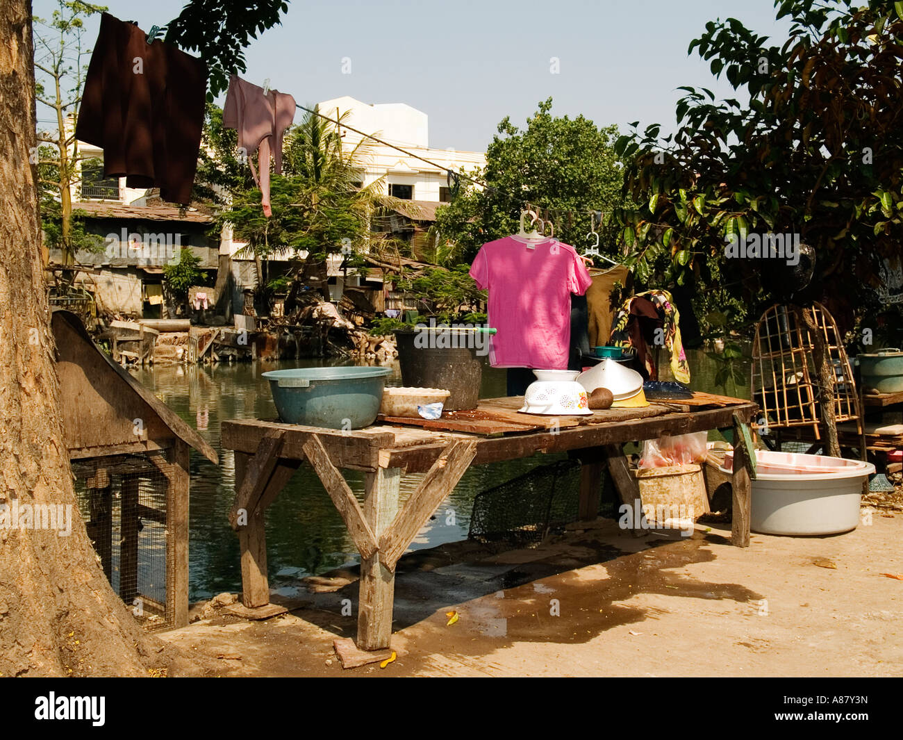 Laundry drying above food preparation table,riverside slum area ...