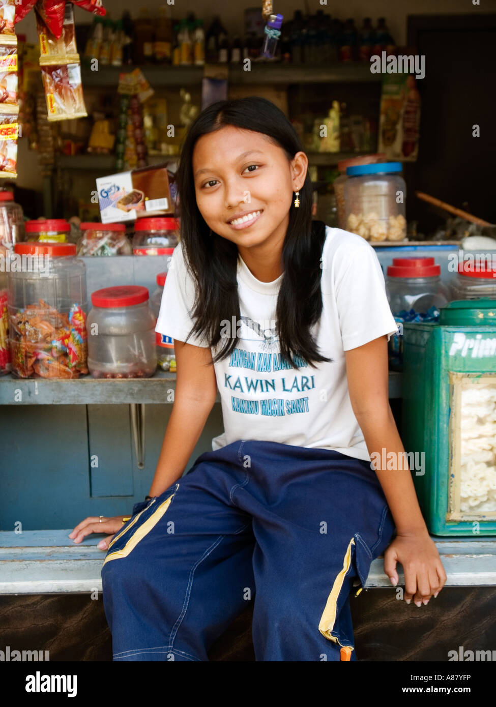 Pretty,young smiling local girl sitting outside of sweet shop,slum area ...