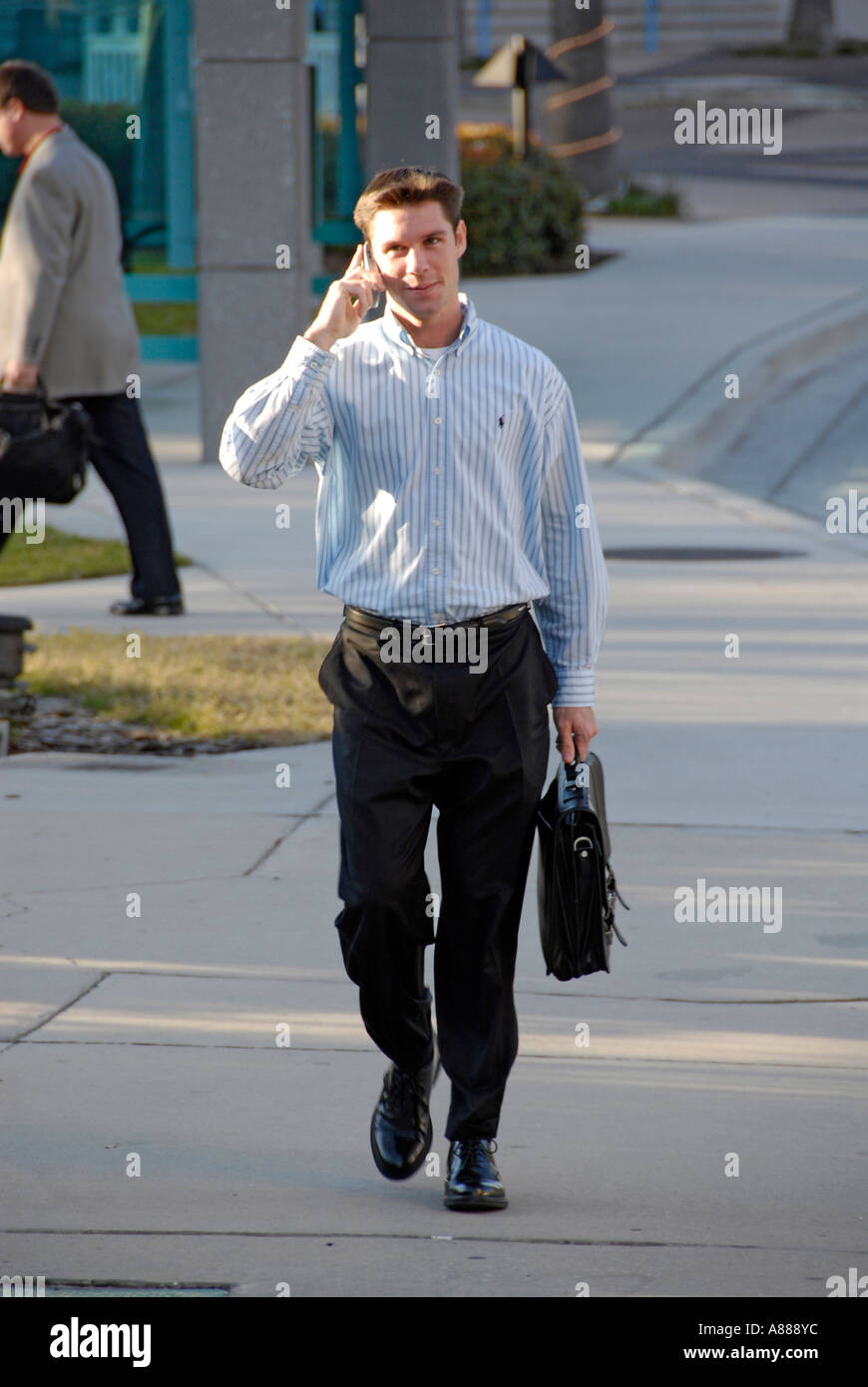 Professional man walking with laptop computer while talking on a ...