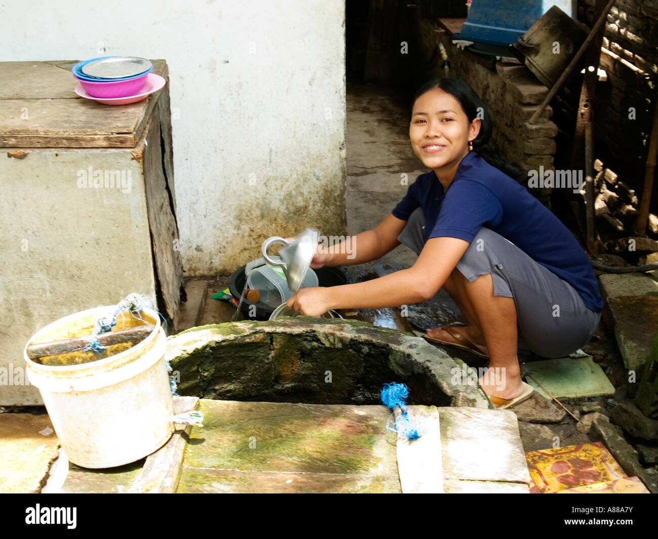 Young local woman washing dishes by well,slum area,Surabaya,Java ...