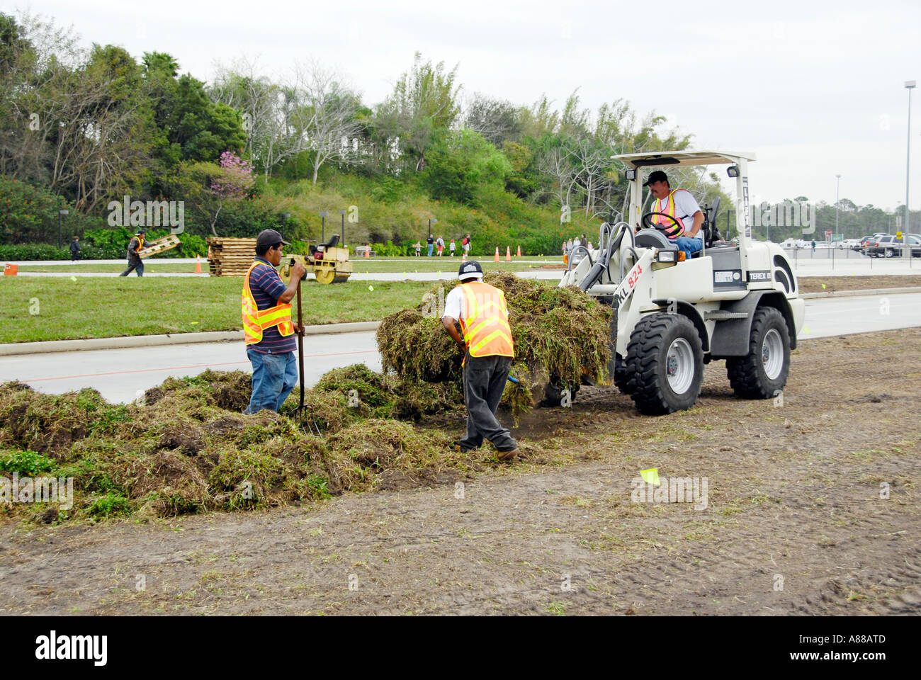 Construction workers clean up and prepare landscape prior to laying new ...