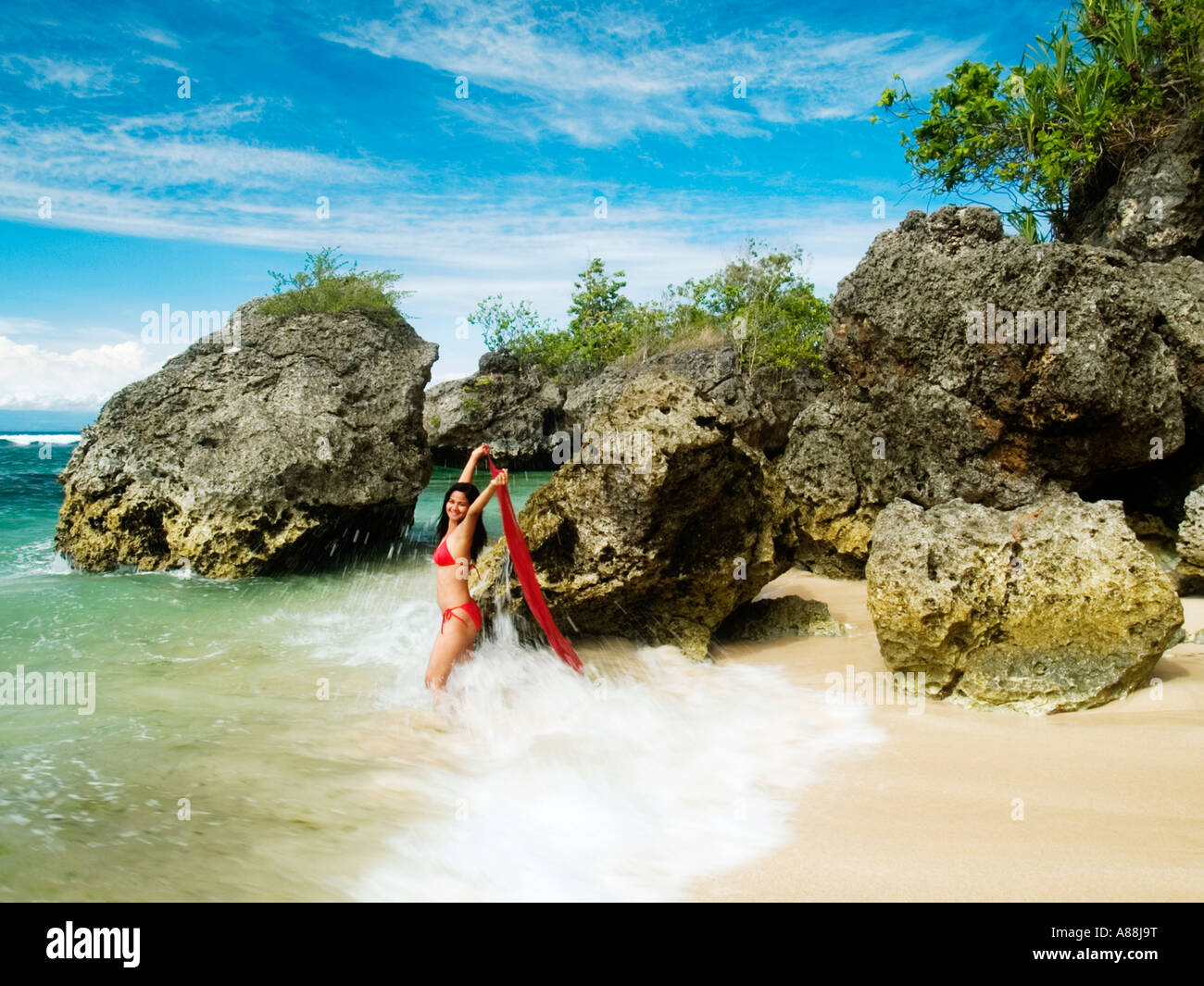 young local woman in red bikini with red sarong at padang padang beach ...