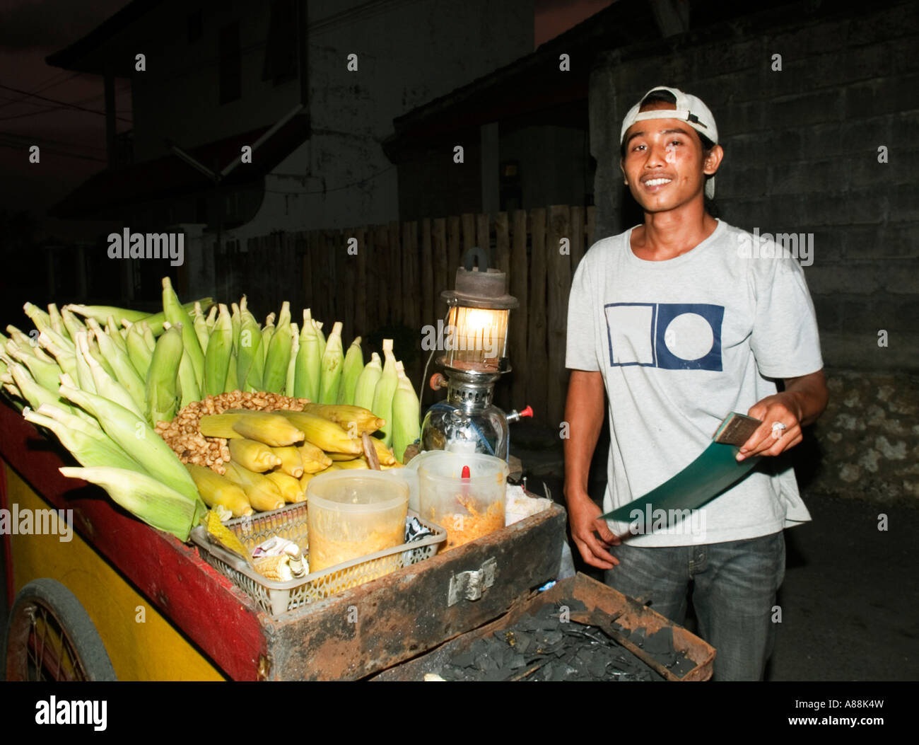 smiling local man selling corn on the cob from his street cart at night ...