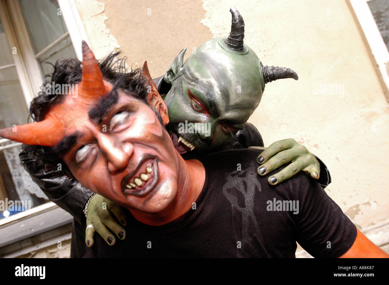 Two horned devils fighting; a green-skinned demon bites the shoulder of ...