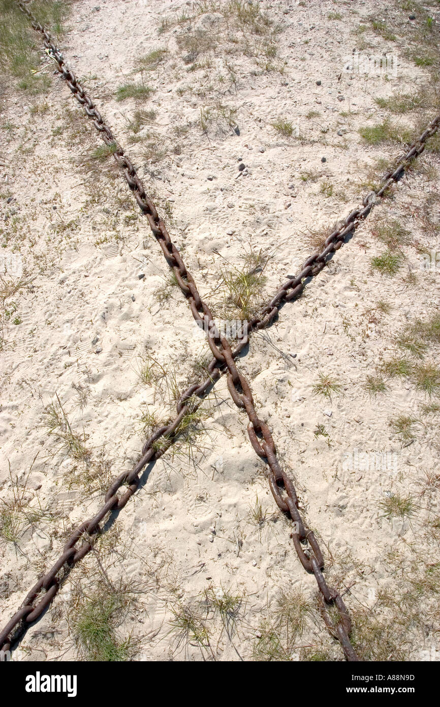Two half buried iron chains forming X character on sand Stock Photo - Alamy