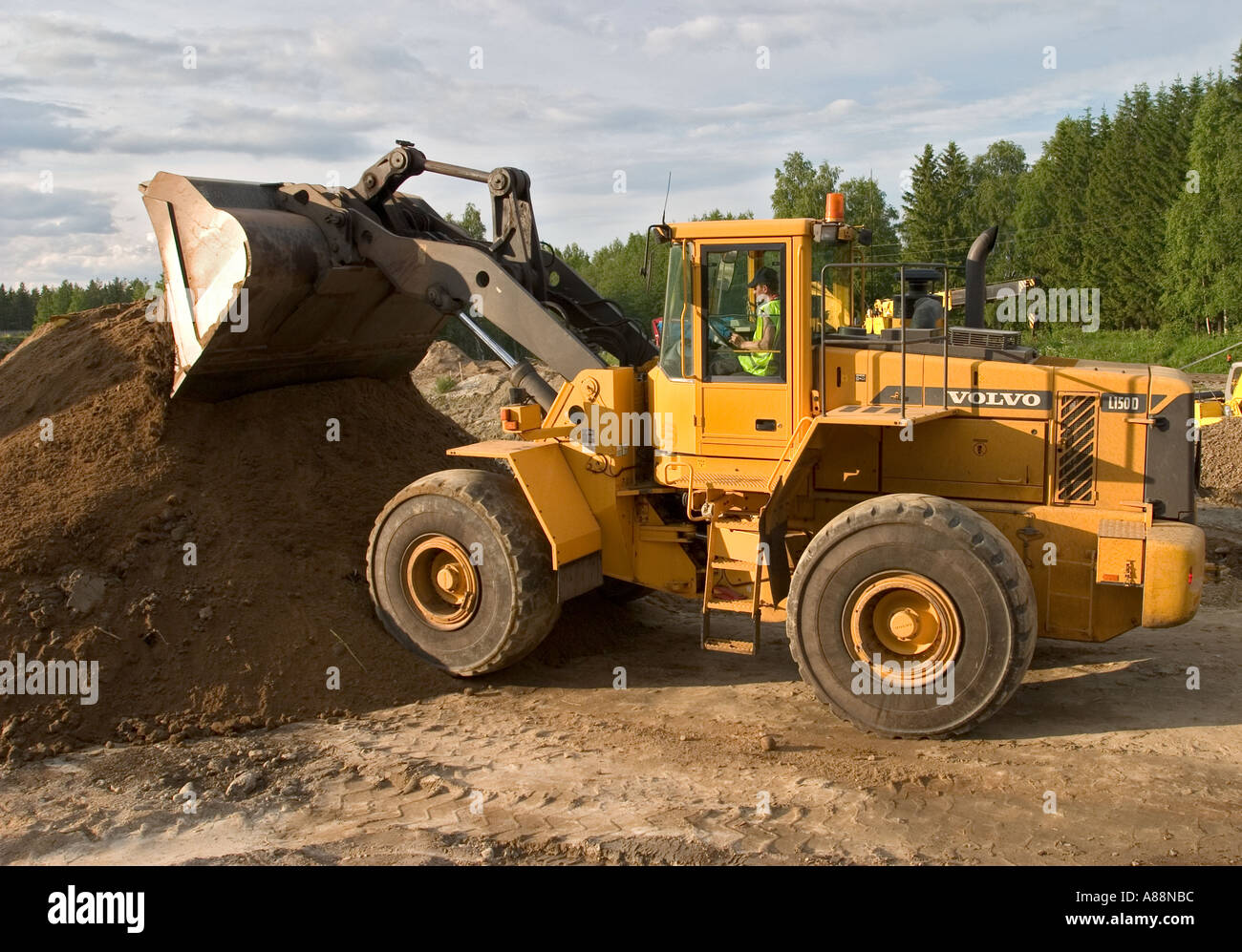 Side profile of a working Volvo front loader piling dirt , Finland ...