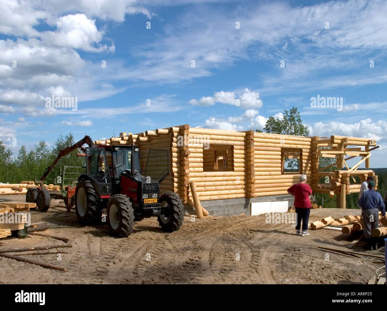 Log cabin under construction and people talking together besides the ...