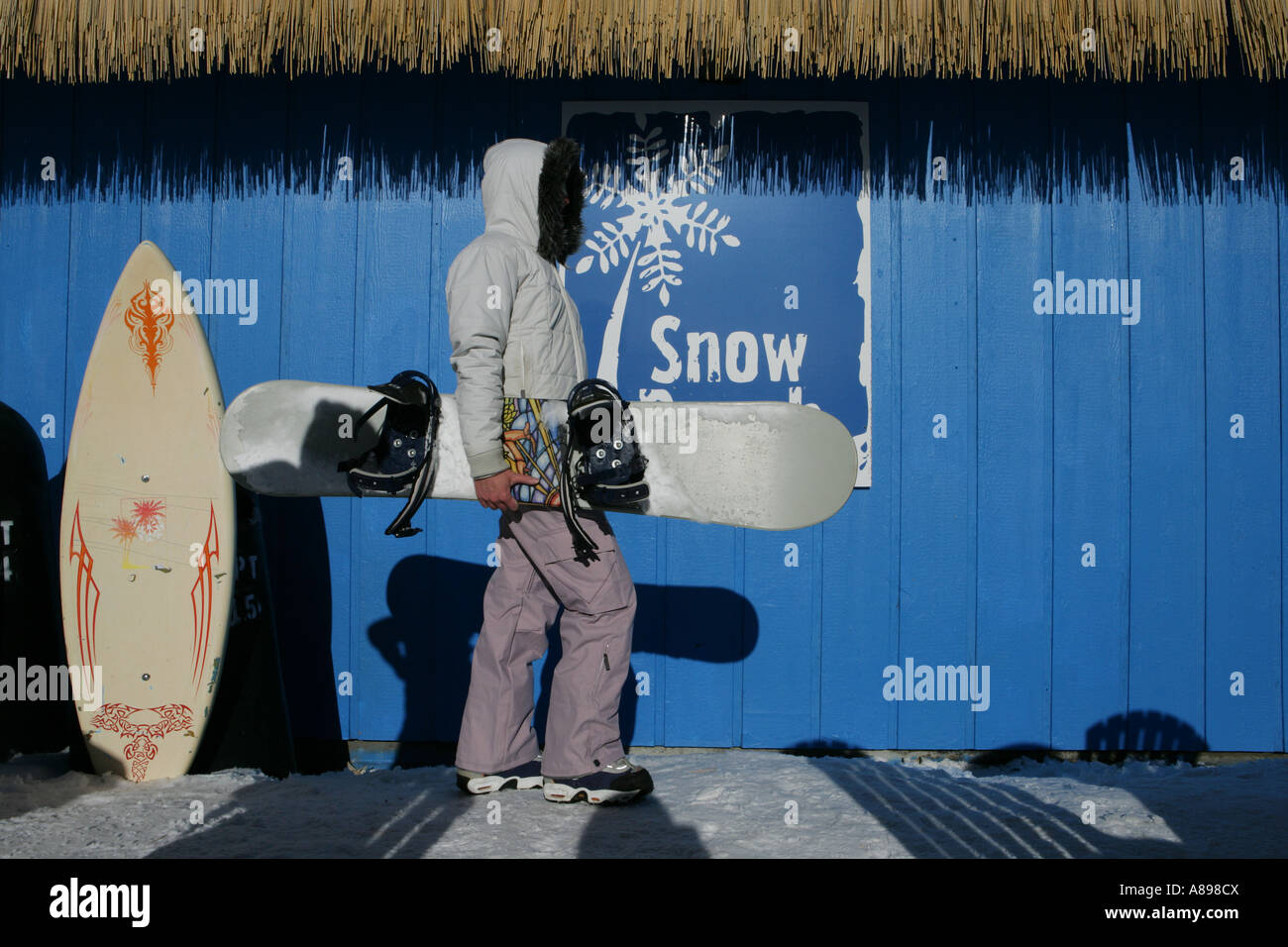 Woman standing sideways holding a snowboard Stock Photo - Alamy