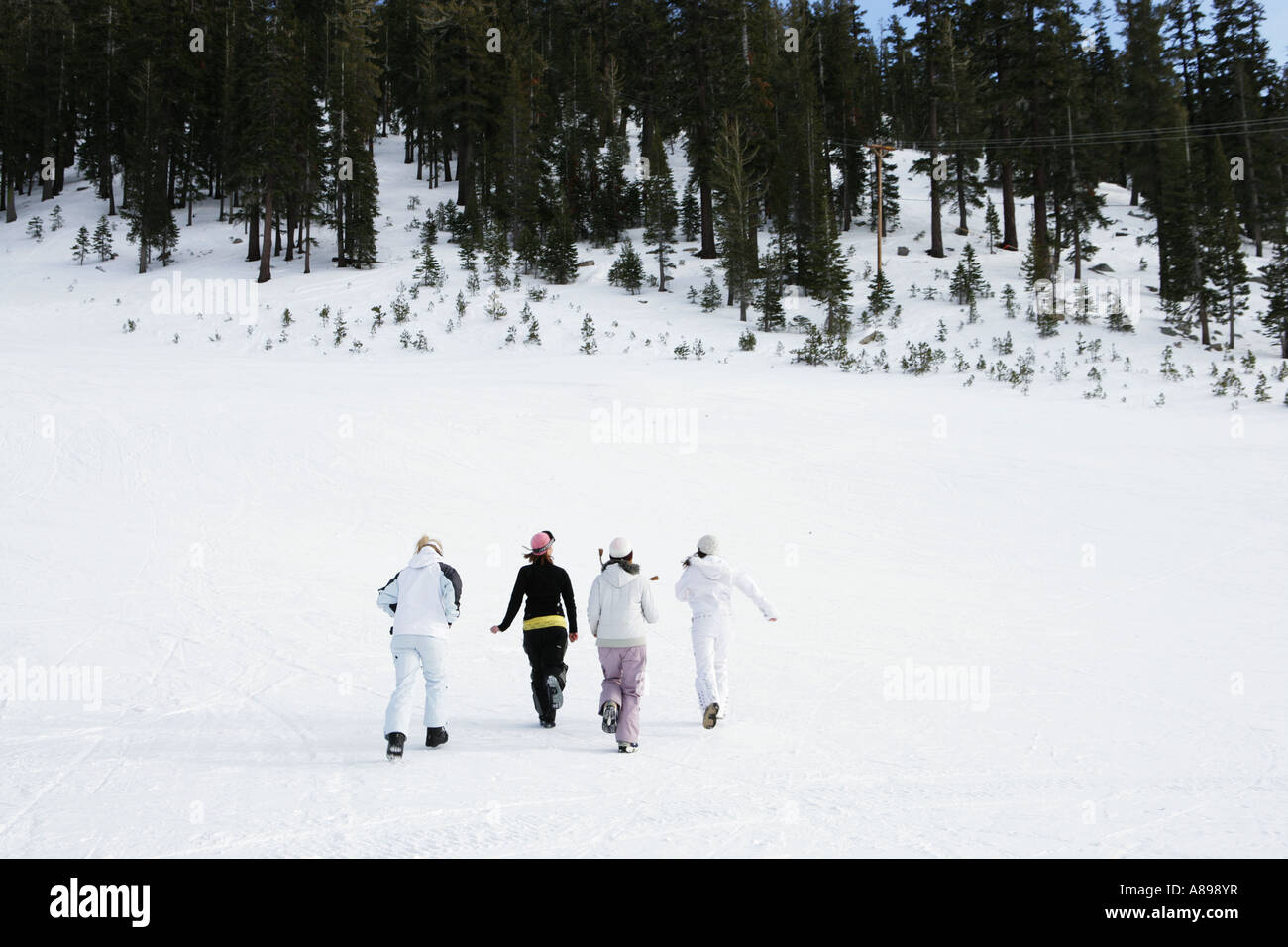 Four people walking down a ski slope Stock Photo - Alamy