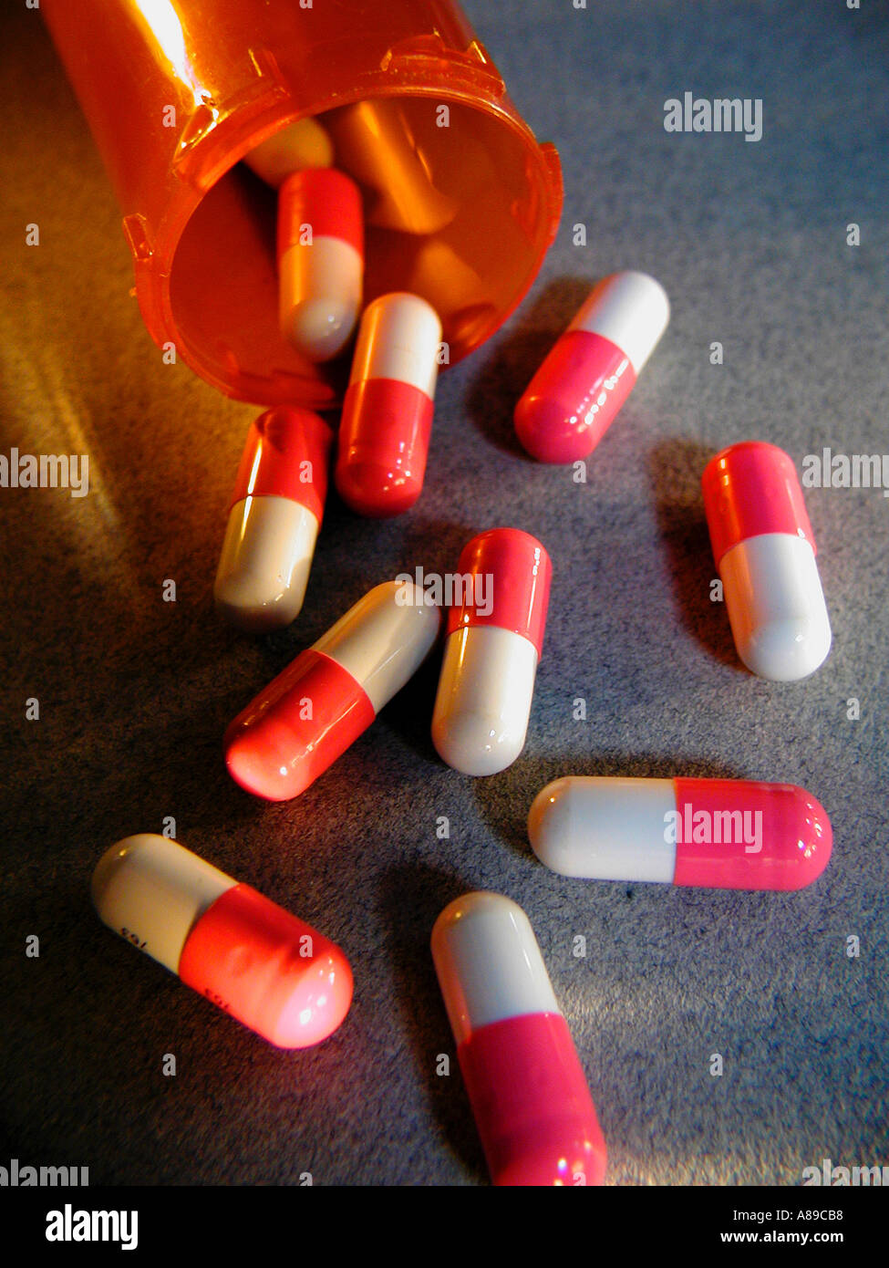 A prescription bottle laying on its side with capsules spilling out of ...