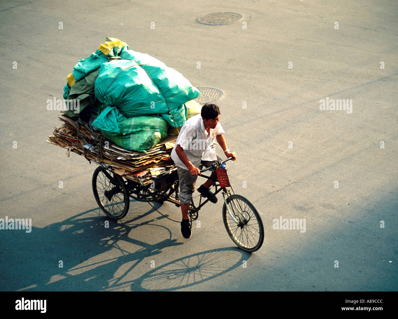 Overhead view of a man riding a bicycle hauling a large load behind him ...