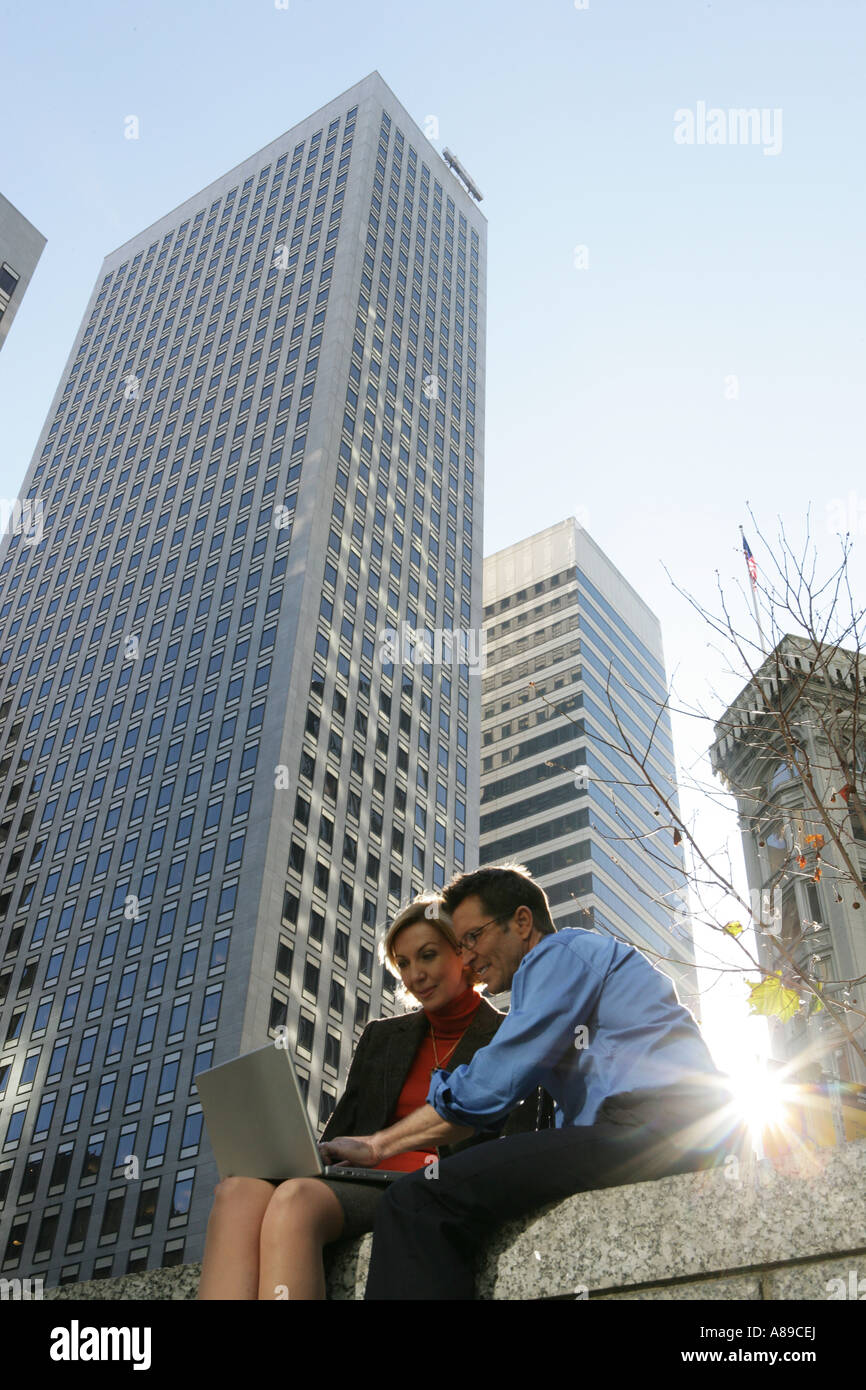 Two people looking at a laptop outside Stock Photo - Alamy