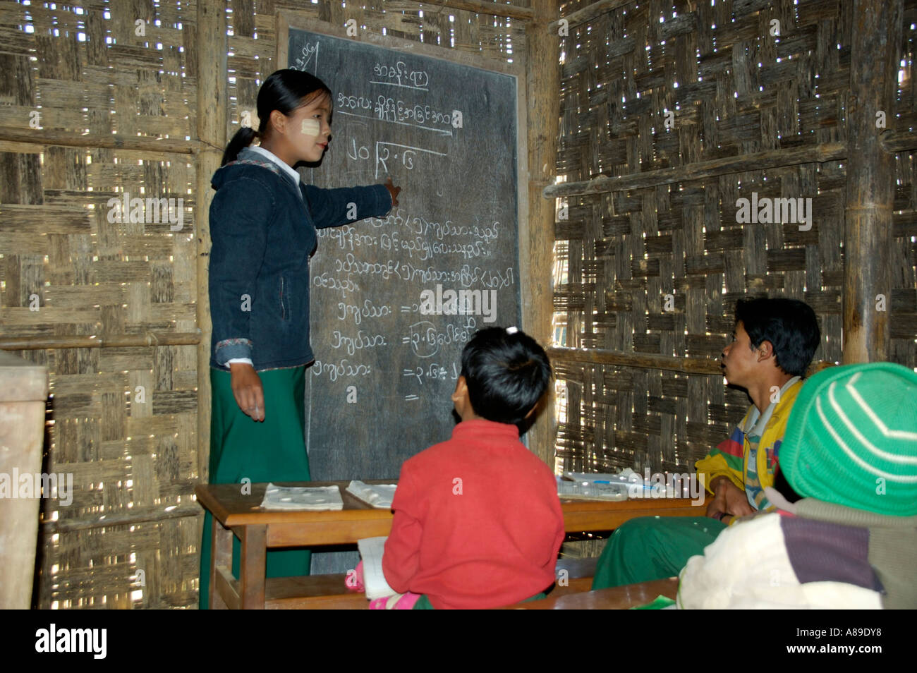 School young teacher at the blackboard with pupils in a bamboo ...