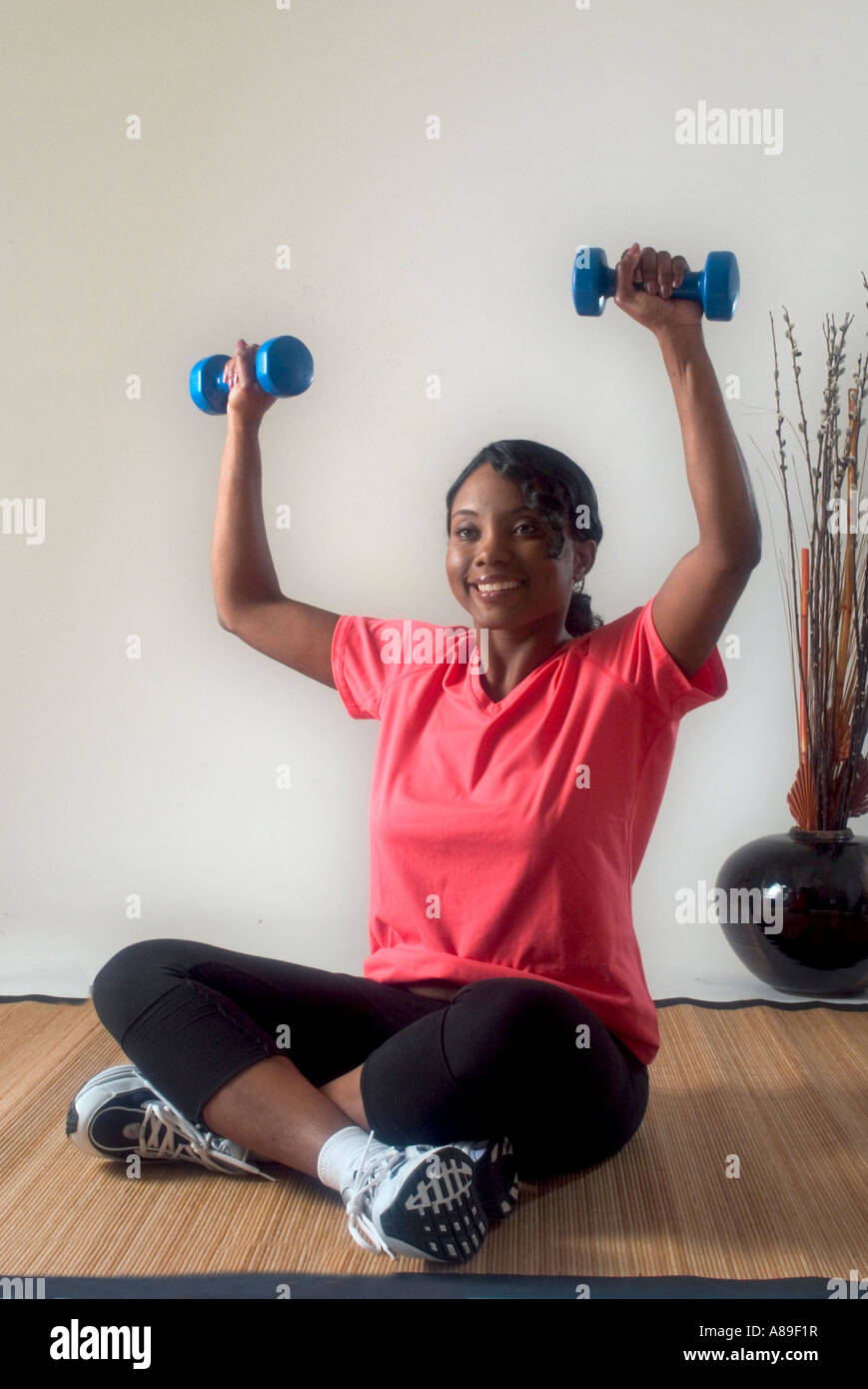 View of a young pretty ethnic black woman lifting dumbbells Stock Photo ...