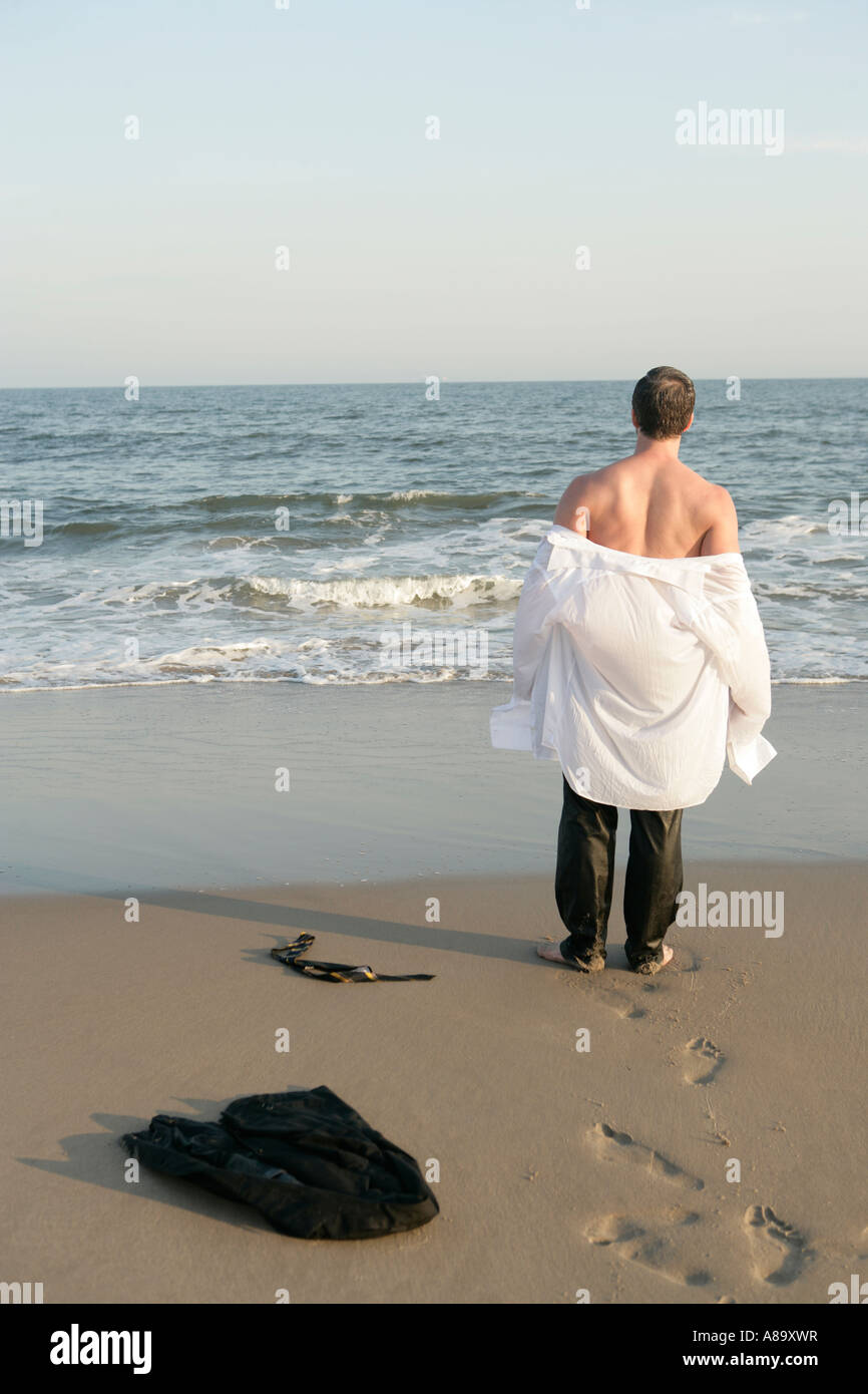 Man standing in sand facing water Stock Photo - Alamy