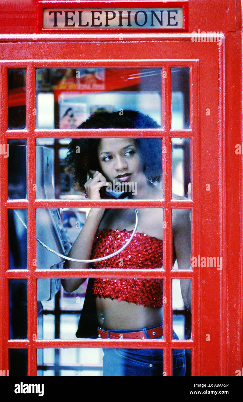 young woman standing in old english red telephone box Stock Photo - Alamy