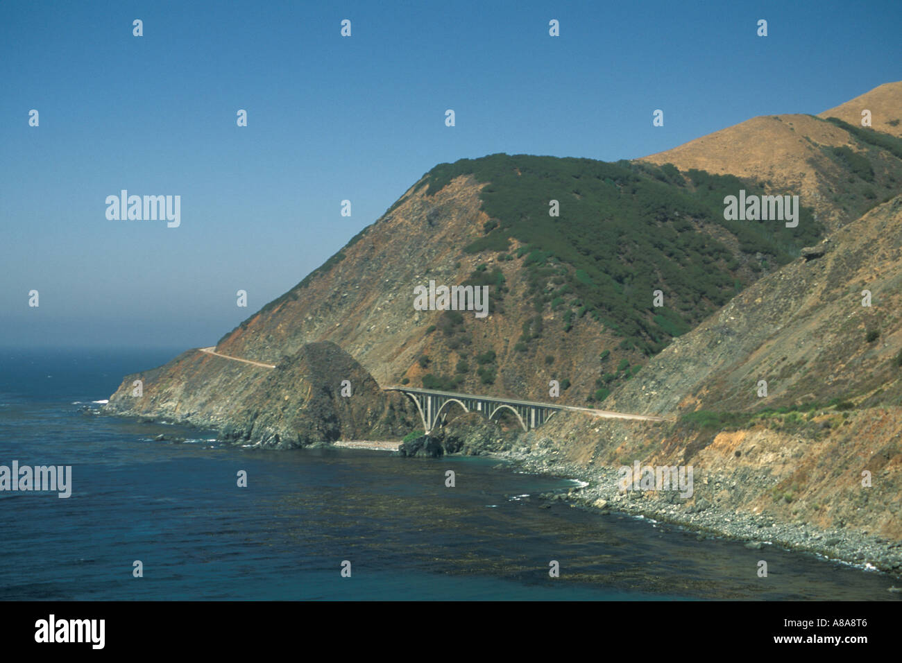 Steep coastal hills and cliffs above bridge along highway one Big Sur ...