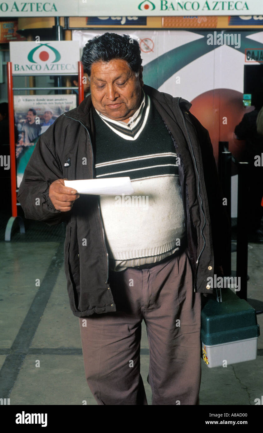 A bank customer checks his balance statement at a Banco Azteca branch ...
