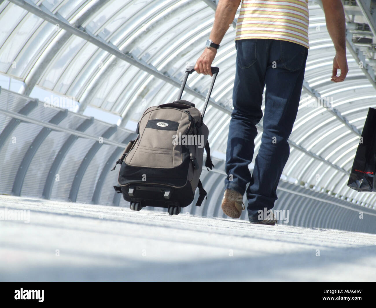 man pulling trolley case in glass gallery Stock Photo - Alamy