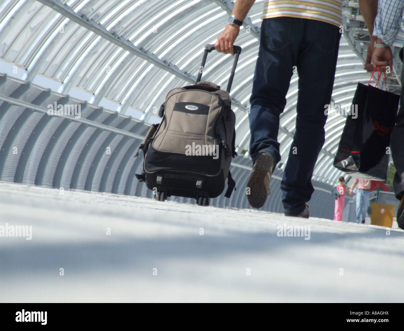 man pulling trolley case in glass gallery Stock Photo - Alamy