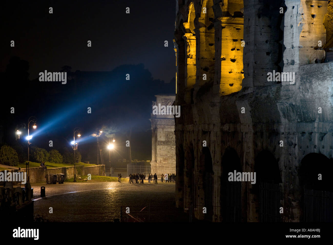 Colosseo at night with light beams and tourists walking nearby Stock ...
