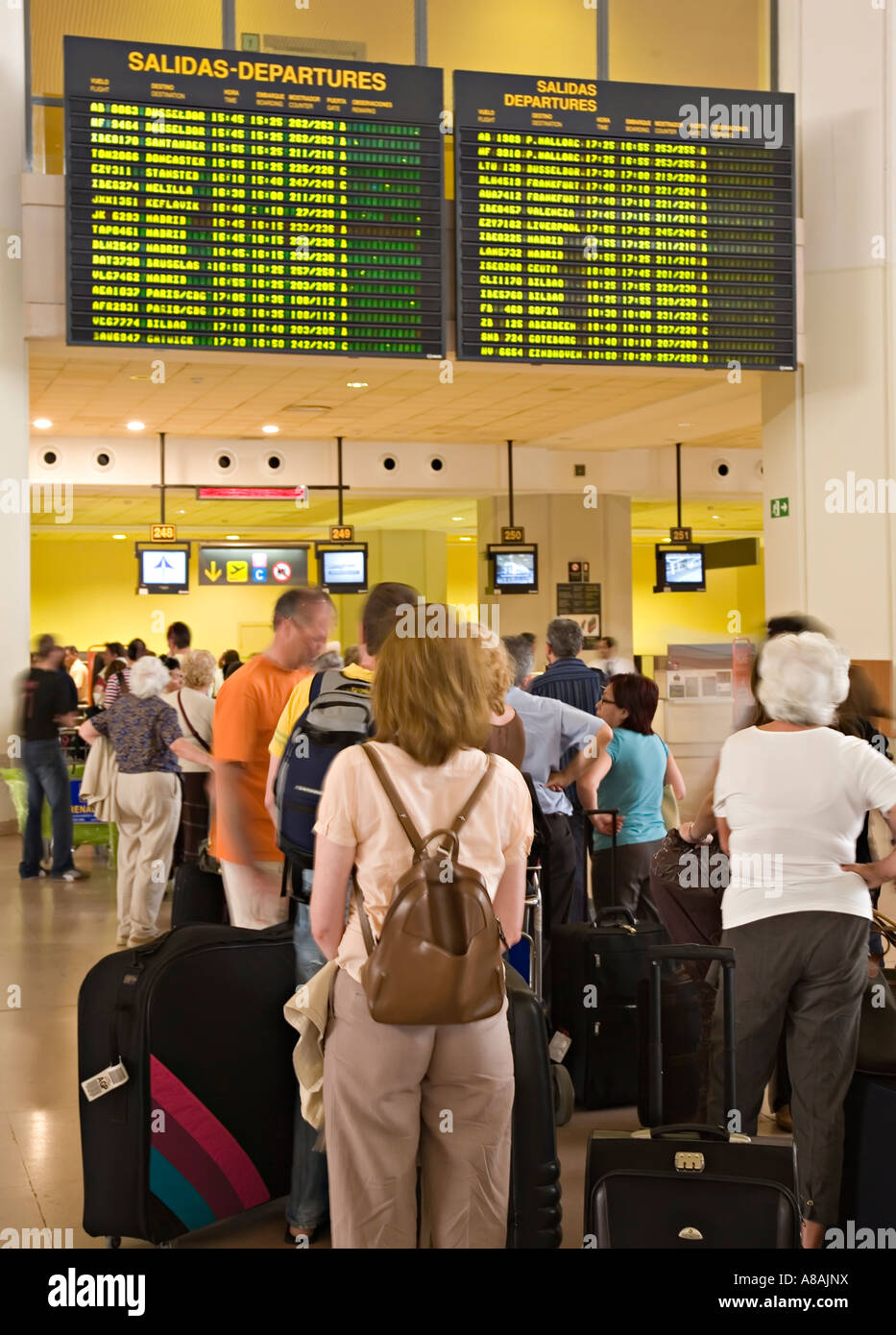 People waiting at check in desks with departure information screens at ...