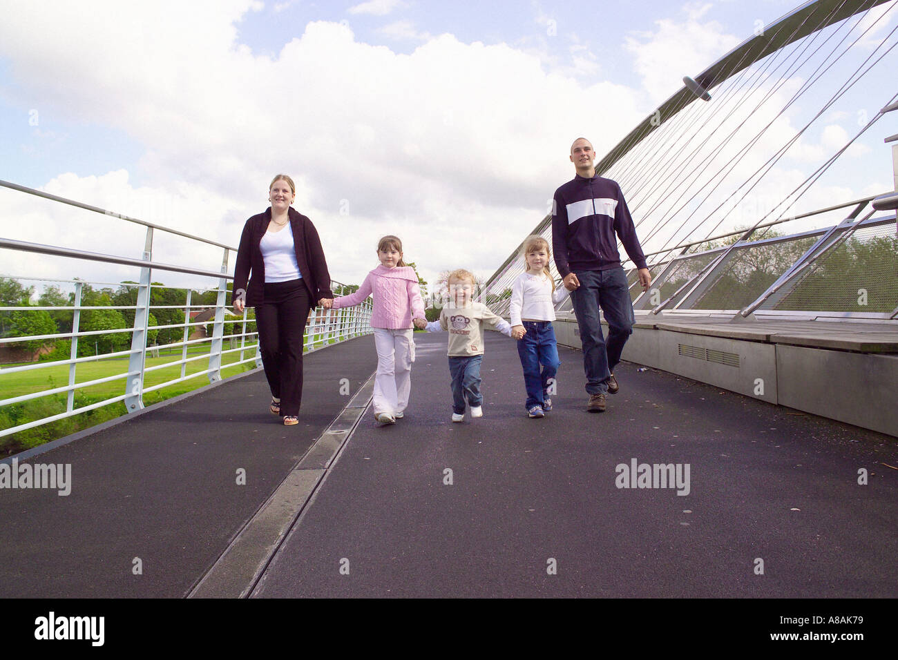 Young man and woman and their 3 young children walking across the ...