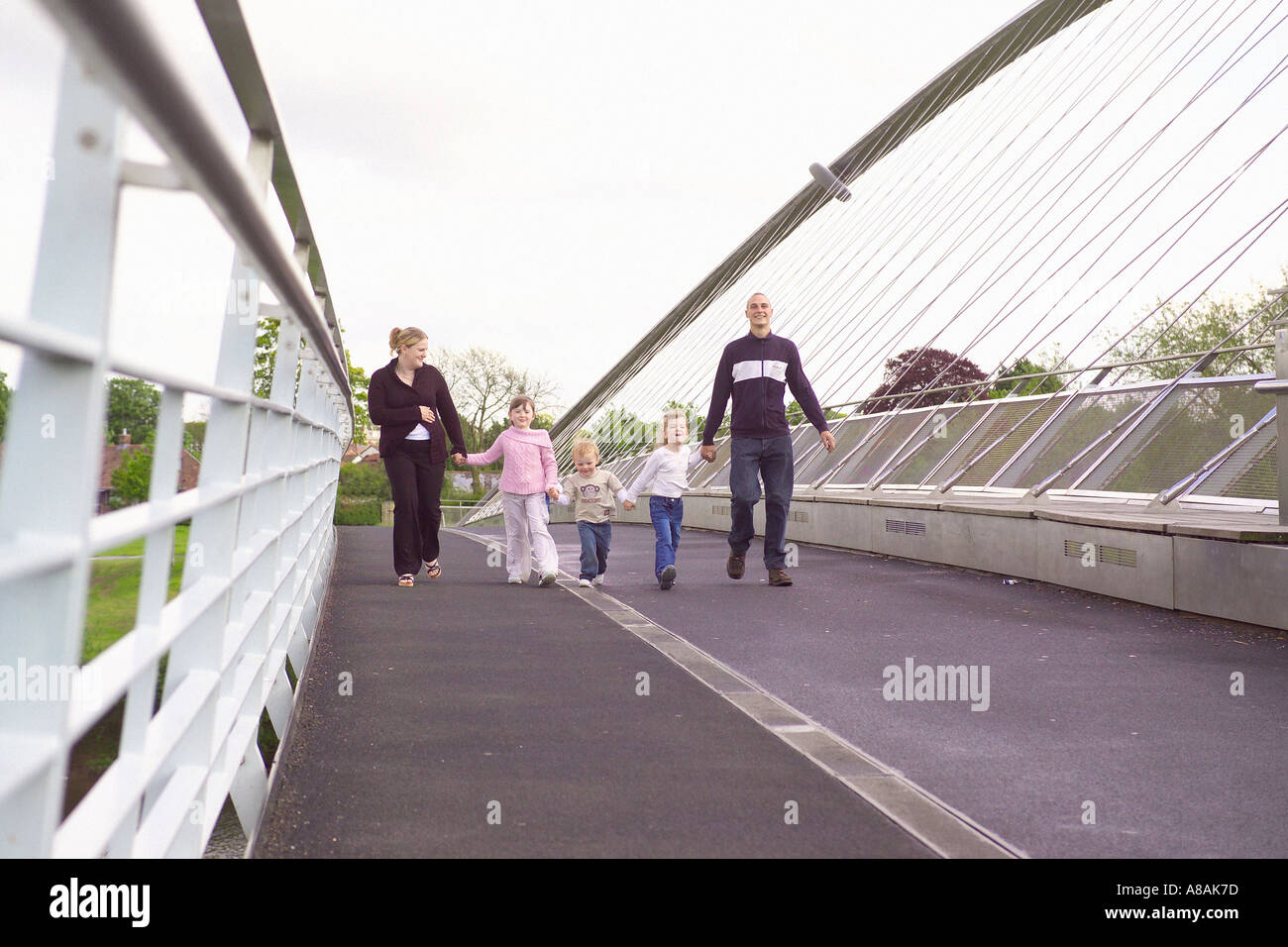 Young man and woman and their 3 young children walking across the ...