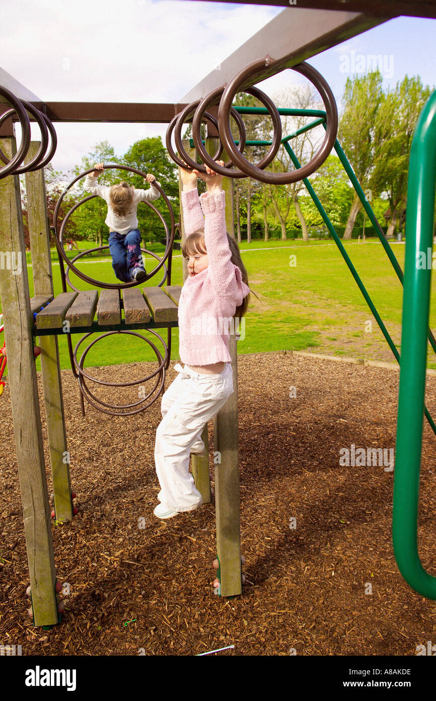 Young caucasian girl swinging from metal tubular rings on a climbing ...