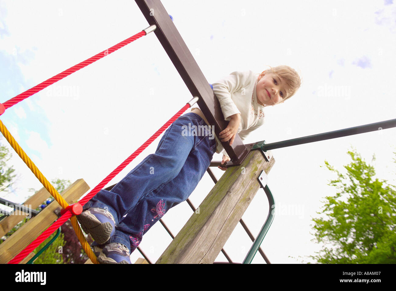 Caucasian child with blonde hair, wearing jeans and a t-shirt, climbing ...