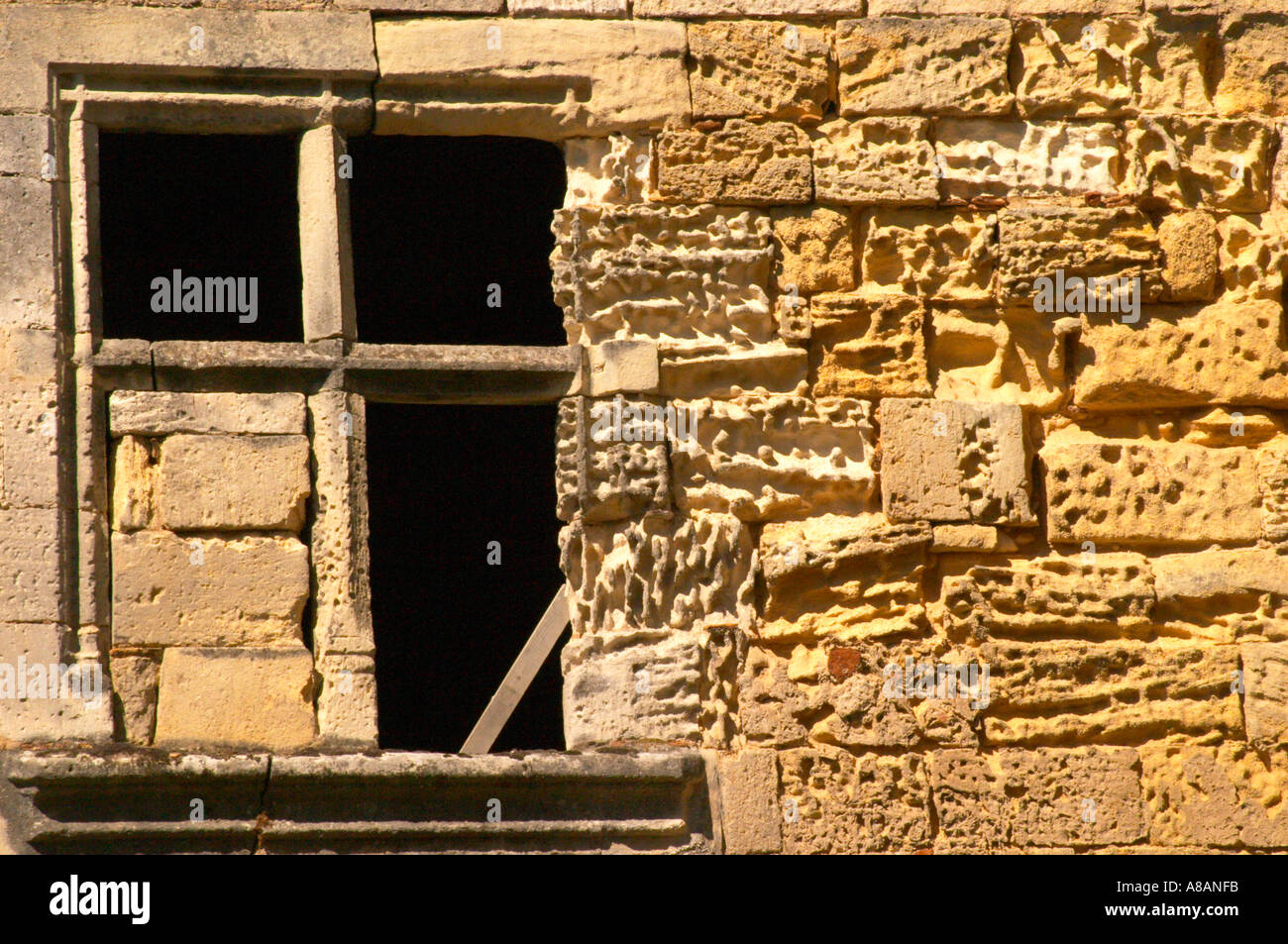 A black empty window in a falling down house with an old stone wall in ...