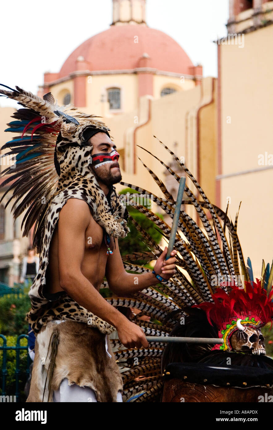 An AZTEC DANCER plays a DRUM in a traditional warrior feathered COSTUME ...