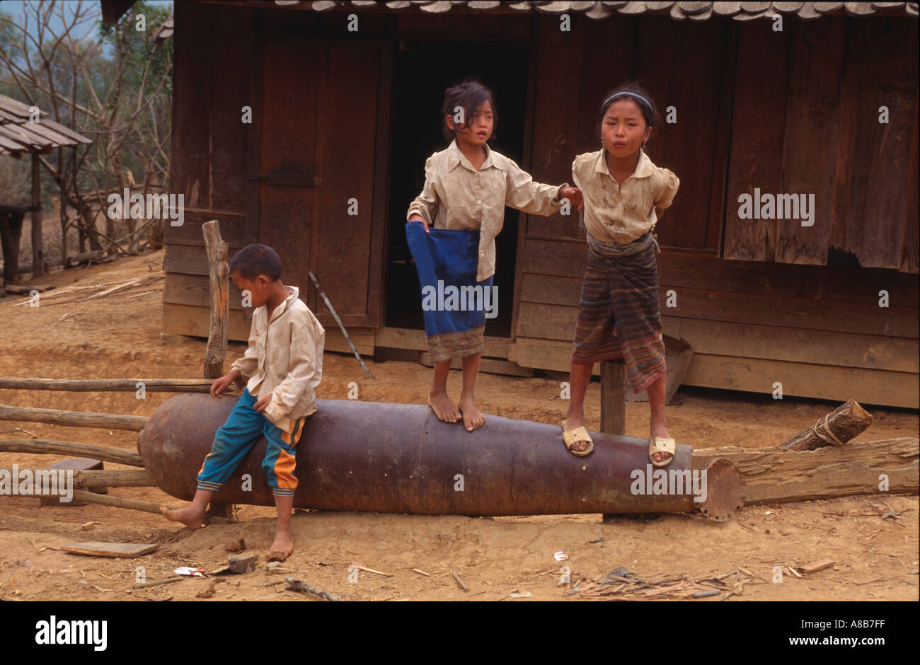 Children playing on a cluster bomb casing fence, Hmong village of Ban ...