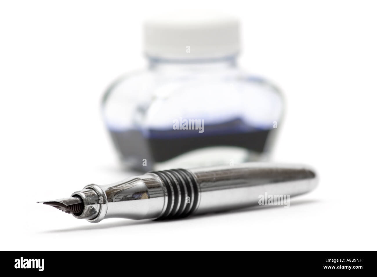Silver fountain pen in front of an ink pot Isolated on a white ...