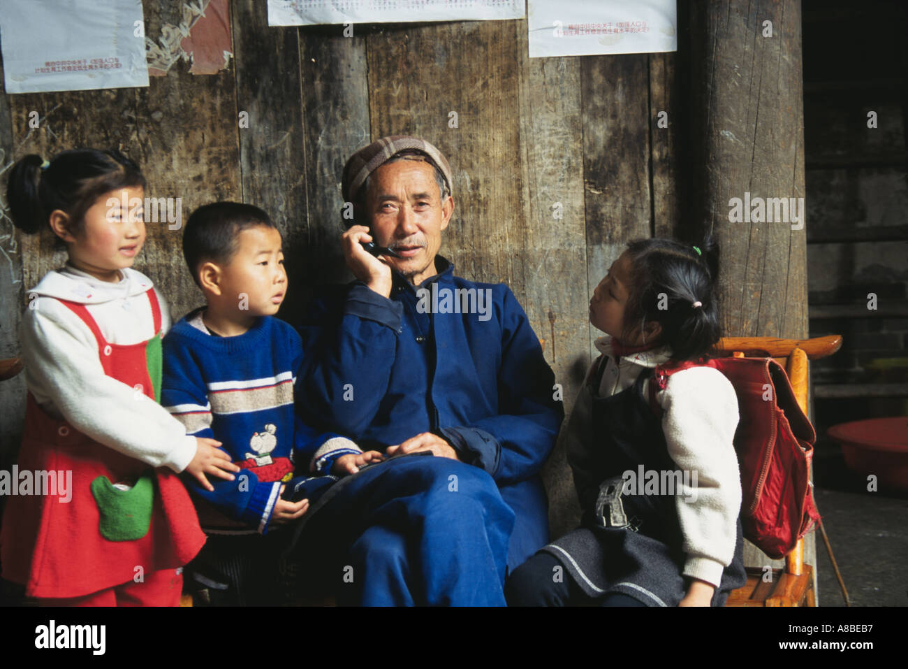 Old man using cellular phone in ancient house with grandchildren around ...
