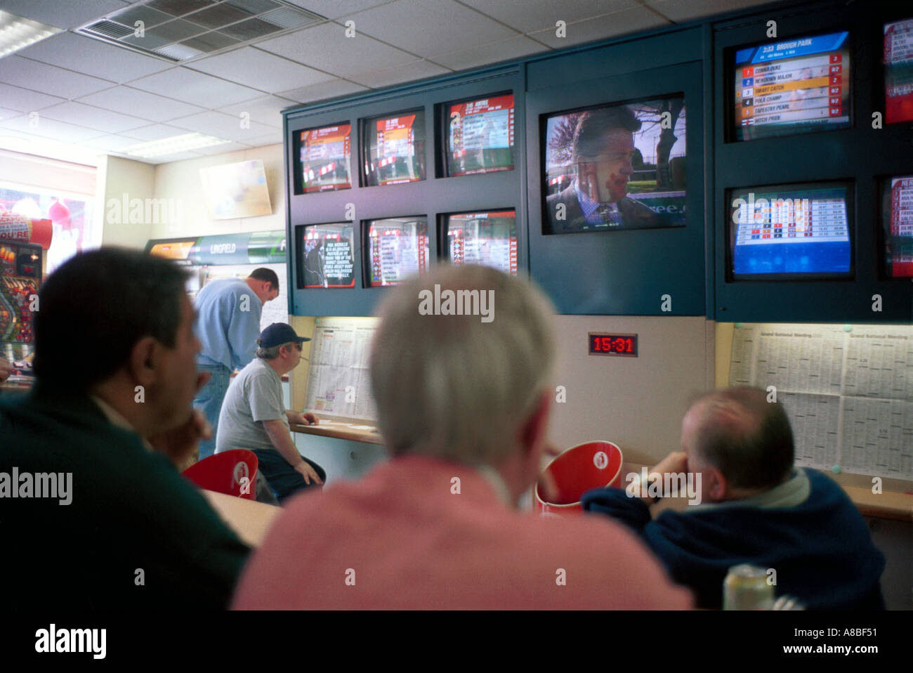 People watching live events on tv screens in a betting shop London UK ...