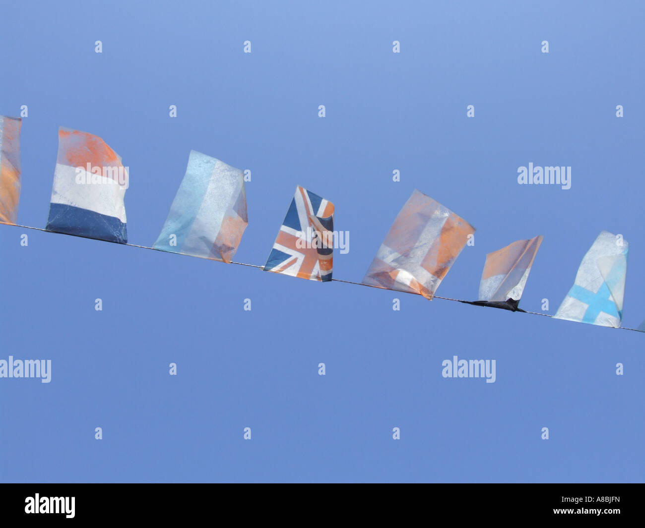 faded plastic flags and blue sky Stock Photo - Alamy