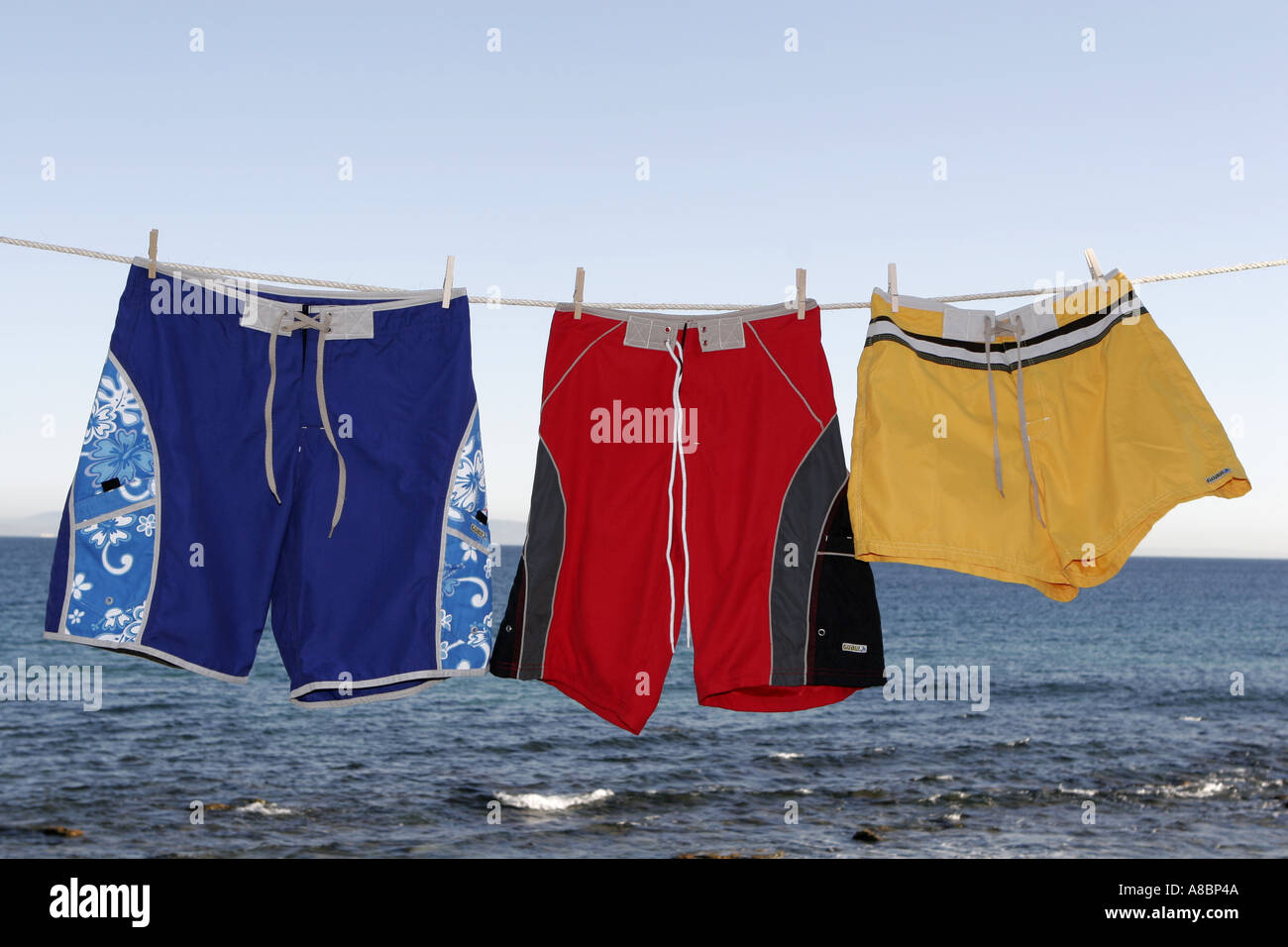 swim suits hanging off clothes line with blue sky background Stock ...