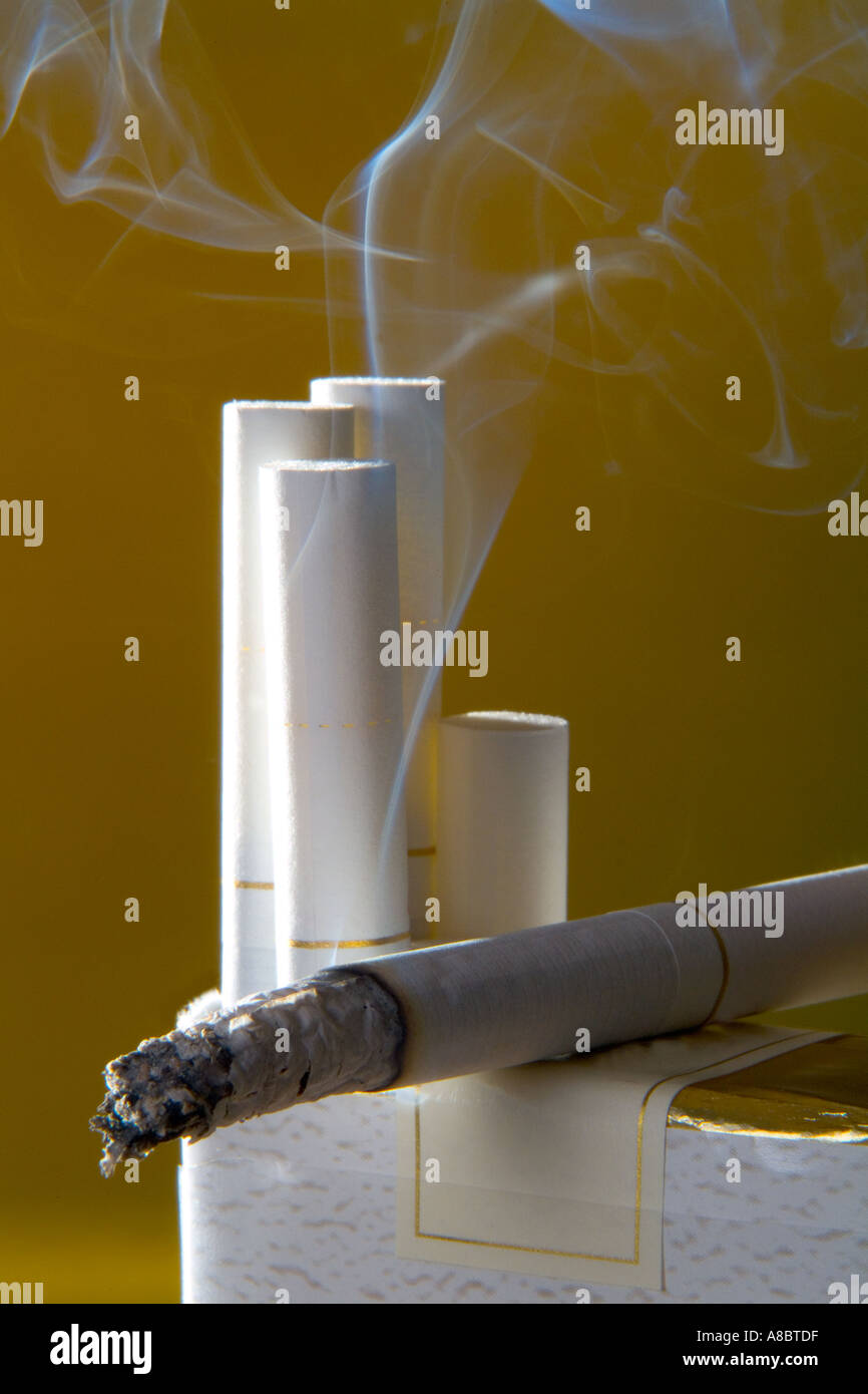 Cigarette pack with smoking cigarette on top Stock Photo - Alamy