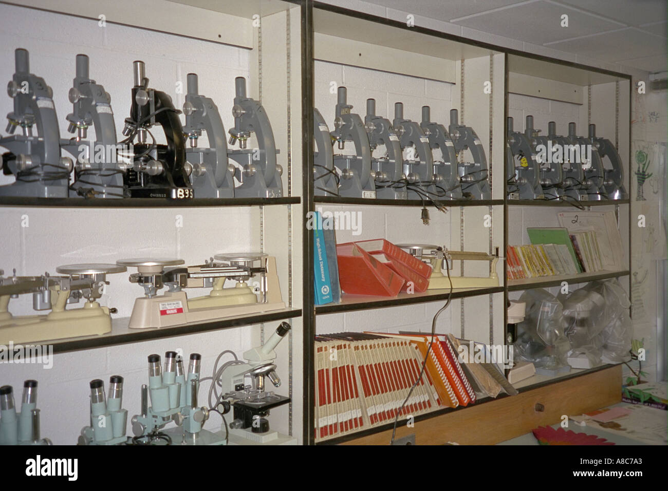 Science school classroom cabinet of microscopes, books and scales ...