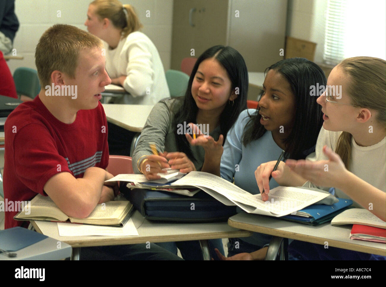 Black Asian American and White students age 15 discussing classroom ...