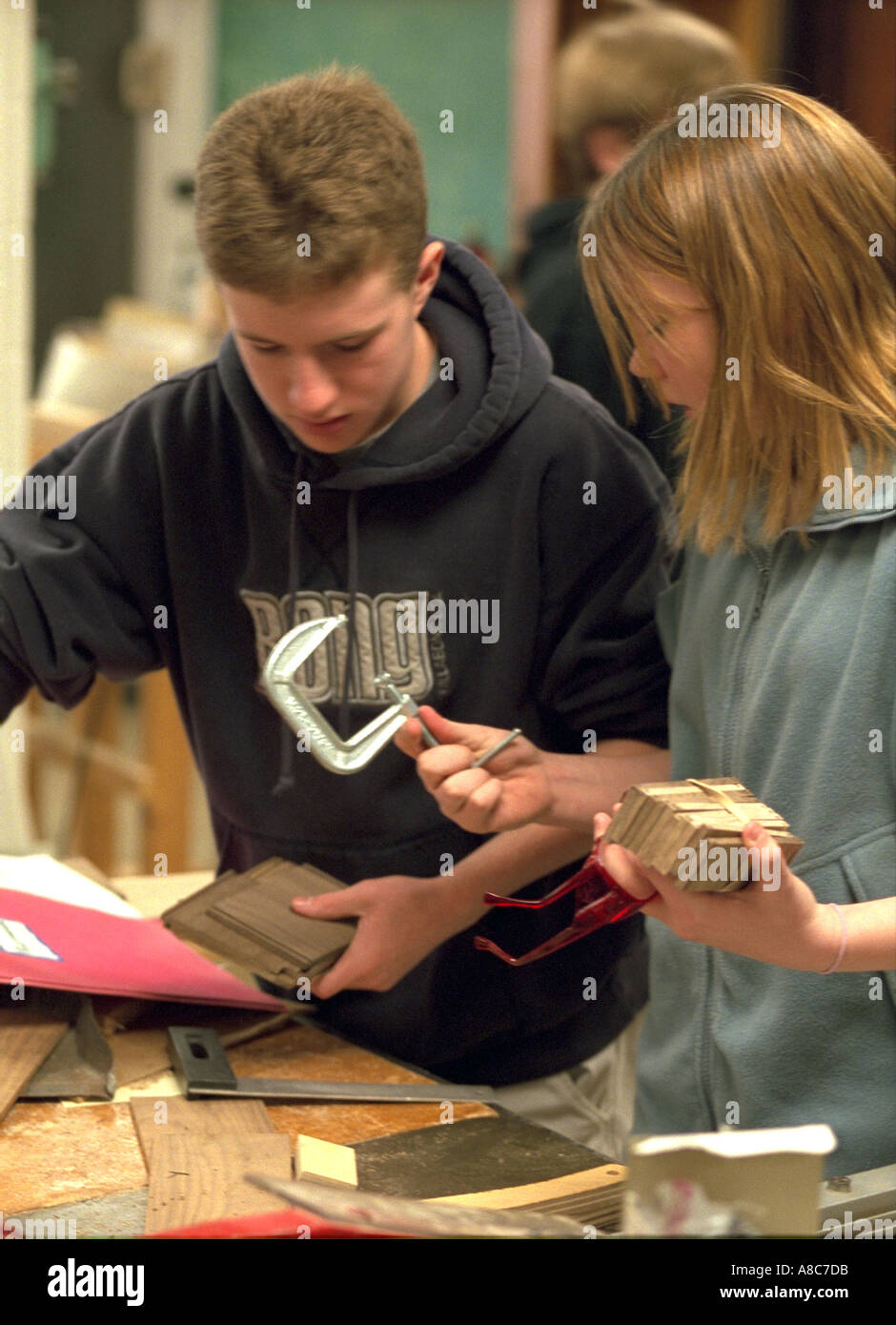 Students age 14 preparing project for gluing with clamp in school shop ...